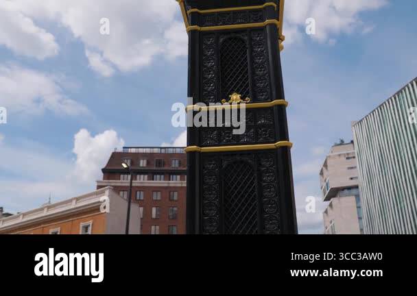A majestic black and gold clock tower in a vibrant city, standing tall ...