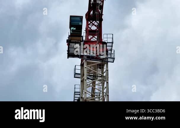 A crane lifts heavy materials against a cloudy sky, showcasing the ...