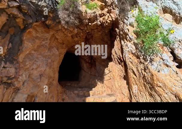 A captivating view of a dark cave entrance surrounded by rugged, rocky ...