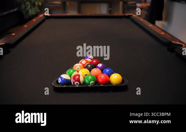 Player breaking racked pool balls in eight ball formation on pool table ...