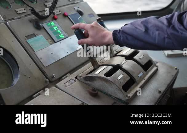 Captain skillfully maneuvering vessel, adjusting levers on bridge ...