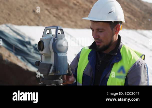 Construction worker operating a theodolite during building operations ...