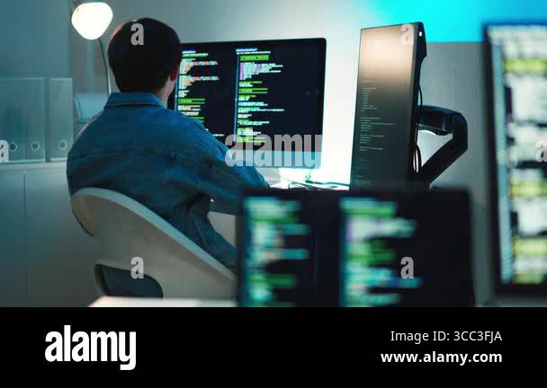 Programmer coding software using multiple screens in modern workspace, working on cybersecurity ...