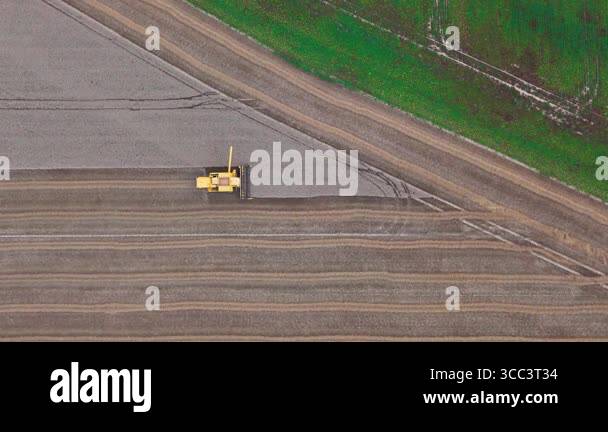 Aerial view of combine harvester progressing across striped ...