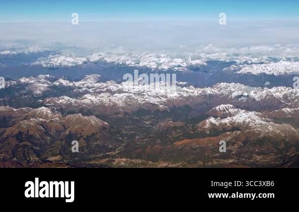Above the peaks with clouds, capped Alps with rugged mountain peaks ...