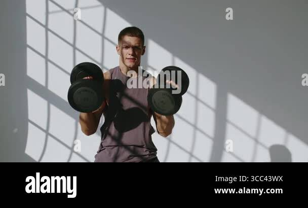 Man with an athletic build trains intensely in a studio, lifting ...