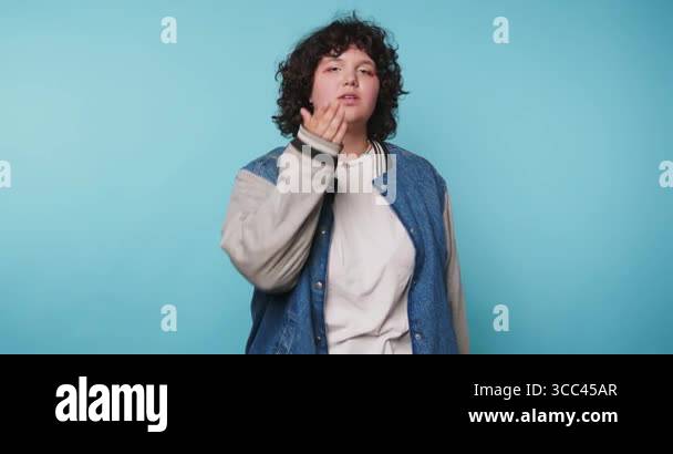 Young person expressing emotions while standing against a blue backdrop ...