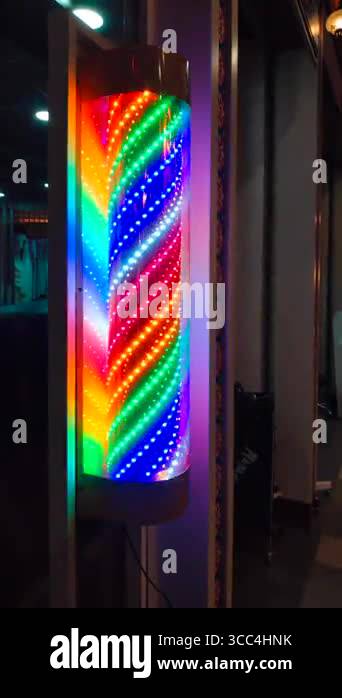 Modern multicolor led light barber pole spinning at the entrance of a ...