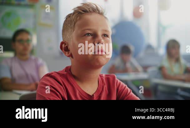 Close Up of Elementary School Boy Sitting at the Desk, Listening to ...