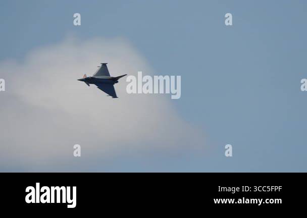 Military jet fighter banking in the sky while performing an acrobatic ...