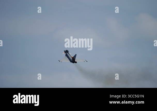 Modern jet fighter flying upward with visible engine exhaust smoke ...
