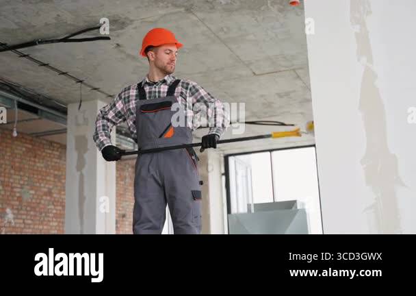 Professional builder wearing safety helmet and work overalls uses a ...