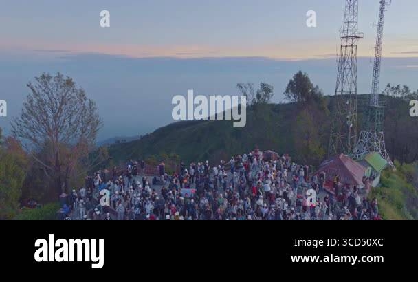 Large crowd gathering near scenic green hillside sunrise Stock Video ...