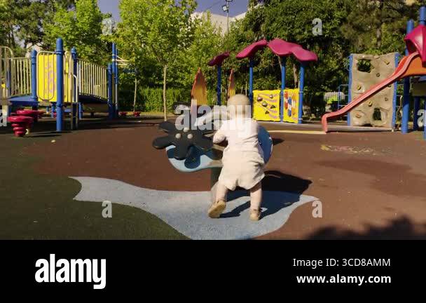Infant interacting with vibrant playground features, enjoying a sunny ...