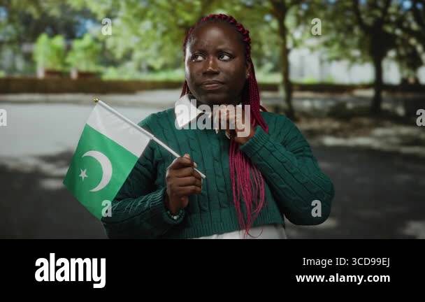 Woman holding pakistan flag outdoors in park with trees in background ...