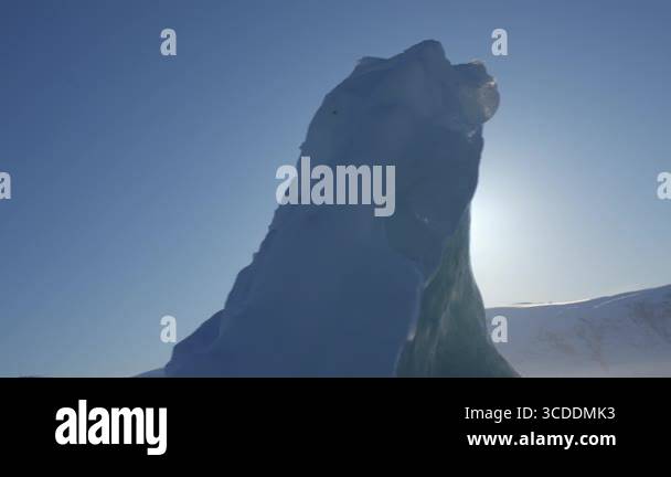 Sun warming a translucent Arctic iceberg that is frozen into solid sea ...