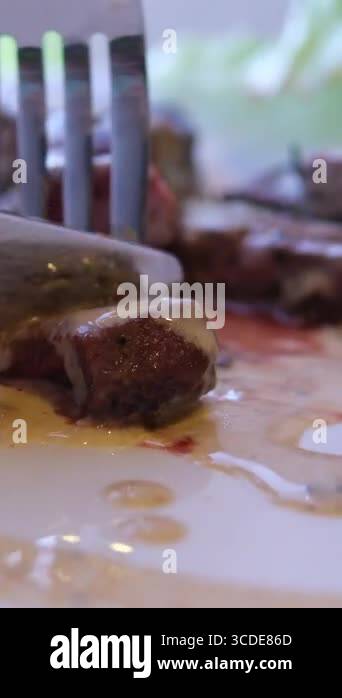 Close-up shot of a knife and fork slicing through a grilled steak on a ...