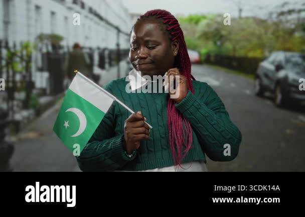 Woman outdoors holding a pakistan flag on a city street looking ...