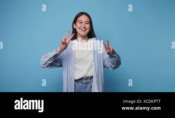 confident young girl displaying a peace sign with a cheerful smile ...