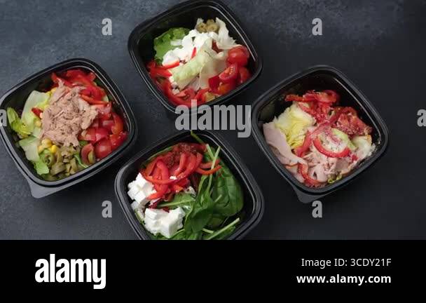 Four diverse fresh healthy salads are beautifully arranged in black ...