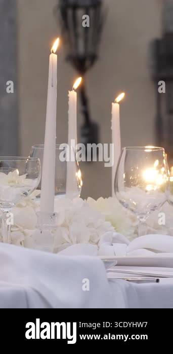 Elegant white wedding table setting with burning candles in front of ...