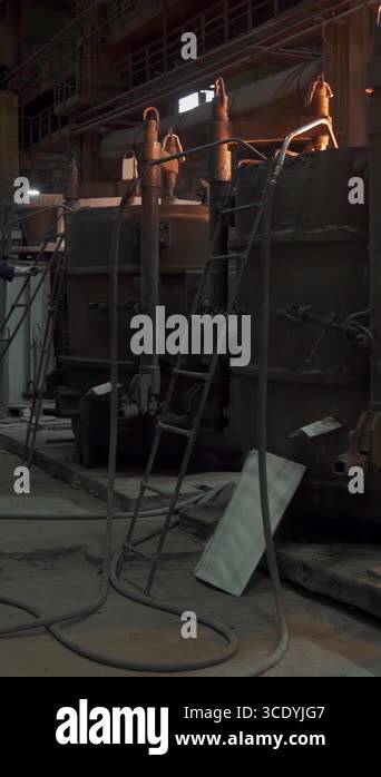 Industrial workers operate a furnace in a metal foundry, showcasing the ...