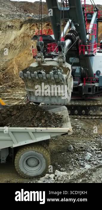 Large excavator loading rocks and minerals into dump truck at mining ...