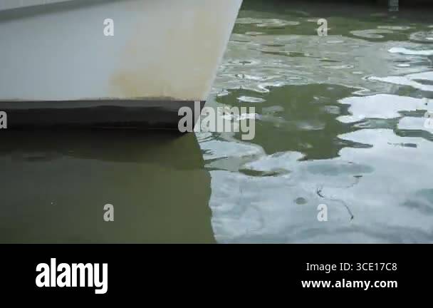 A closeup of a boats hull reflected in calm water, showcasing ripples ...