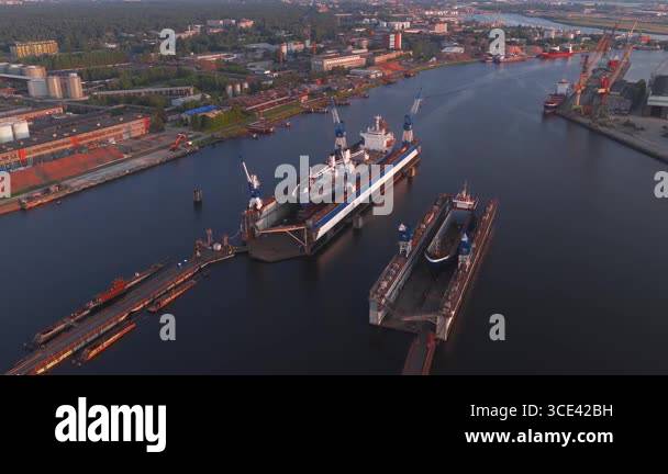 A shipyard in Riga, Latvia during sunset, featuring dry docks, cranes ...