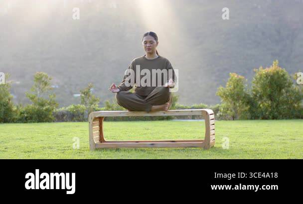 Sunbeam guiding Asian woman walking onto bench on lawn, sitting in ...