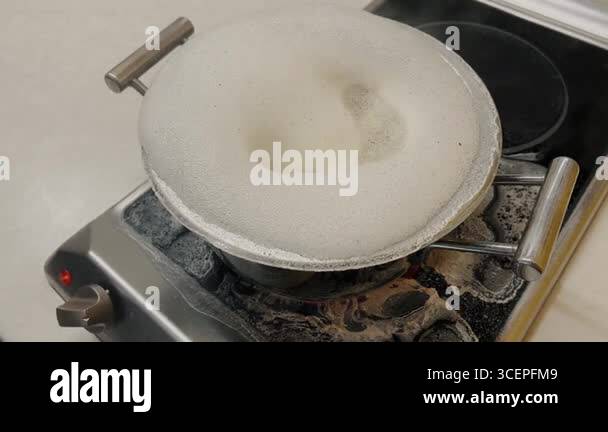 A woman's hands turn off the burner and remove a pot from the stove ...