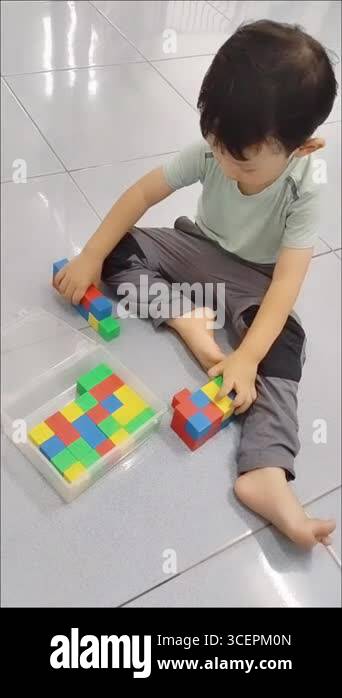 A young child focuses intently on building with colorful blocks ...