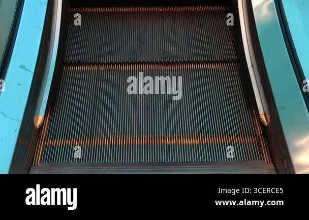 Moving escalator steps ascending with side panels and visible safety ...