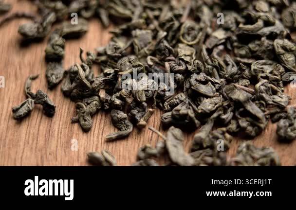 Dried curled leaves of chinese traditional green tea on wooden texture ...