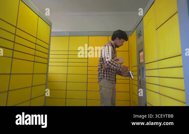Yellow self-service postal terminal. Man sending parcel. Parcel pick up ...