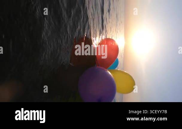 Bunch of multi-colored balloons tied with ribbon floating on surface of ...