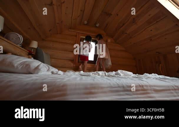 Young girls observe the world from their rustic log cabin bedroom ...