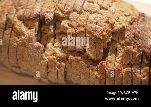 Overhead view of sliced bread loaf. A crusty bread loaf rotates under ...