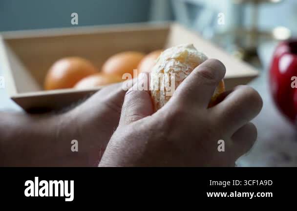 Peeling Orange Close-Up. Hands carefully peel a ripe orange, revealing ...