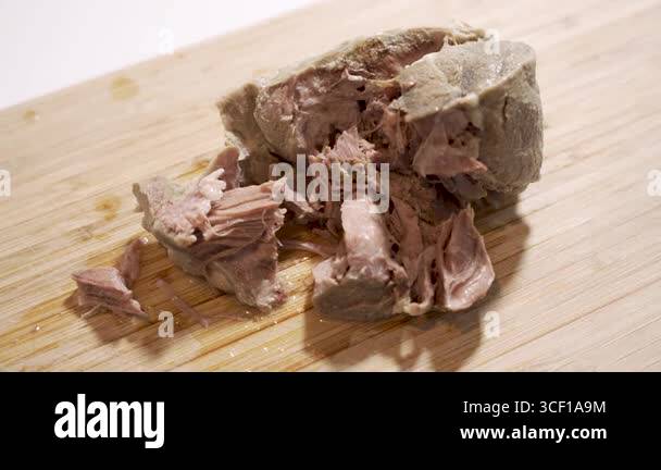 Cooked meat chunk on board. A chunk of boiled meat rotates on a wooden ...