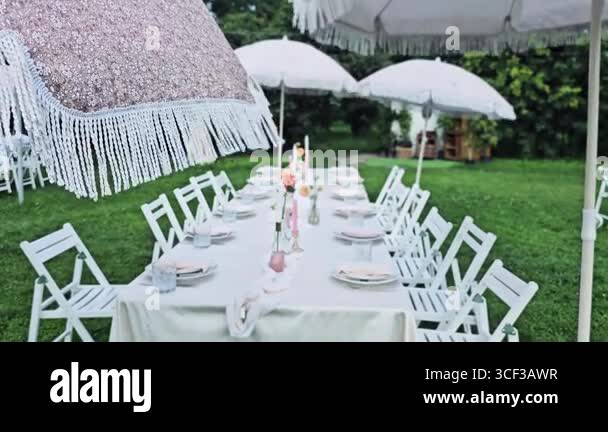 Table neatly set up outside for guests during a wedding reception on a ...