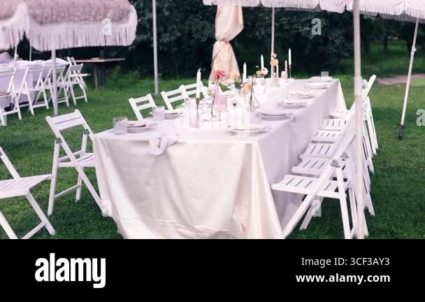 Table neatly set up outside for guests during a wedding reception on a ...