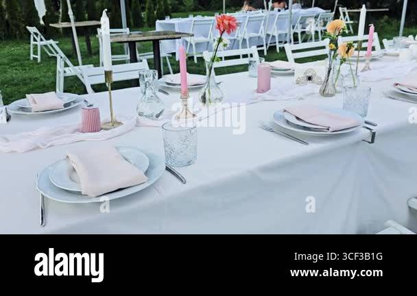 Table neatly set up outside for guests during a wedding reception on a ...