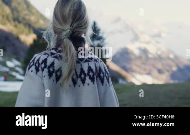 Blonde girl 7 years old walking along alpine valley, approaching ...