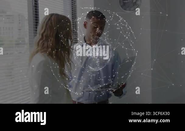 Colleagues standing near blinds and wall clock tapping tablet causing ...