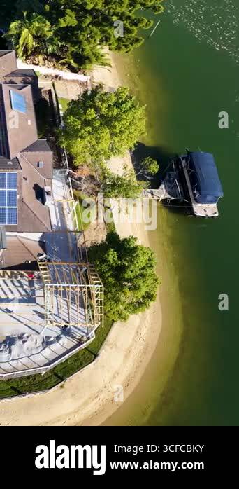 Aerial drone footage orbits a modern waterfront mansion with solar ...