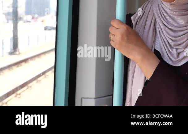 A woman stands on a train, holding the rail while enjoying the ride ...