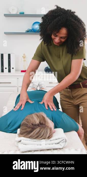 A professional Black woman biokineticist gently provides back ...