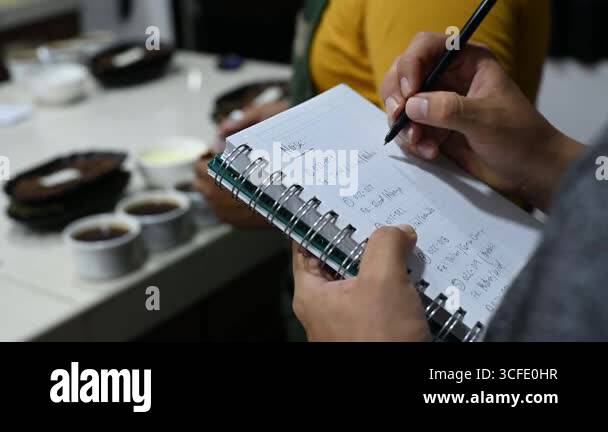Person writing down key points in a notebook at a cafe school meeting ...