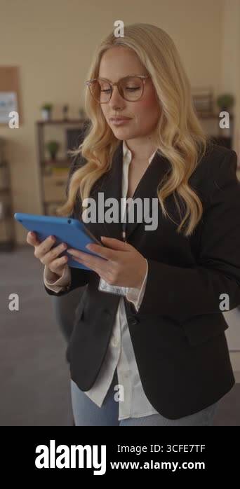 Woman smiling in an office holding a tablet with blonde hair and ...